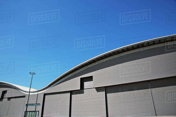 Curved roof of warehouse and blue sky - Royalty-free Stock Photo | Dissolve