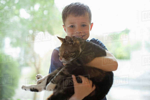 Smiling boy holding cat indoors - Royalty-free Stock Photo | Dissolve