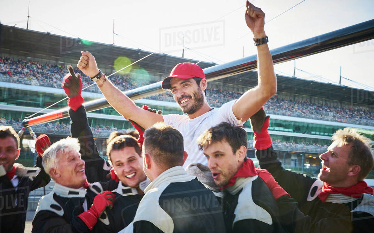 Formula one racing team carrying driver on shoulders, celebrating ...