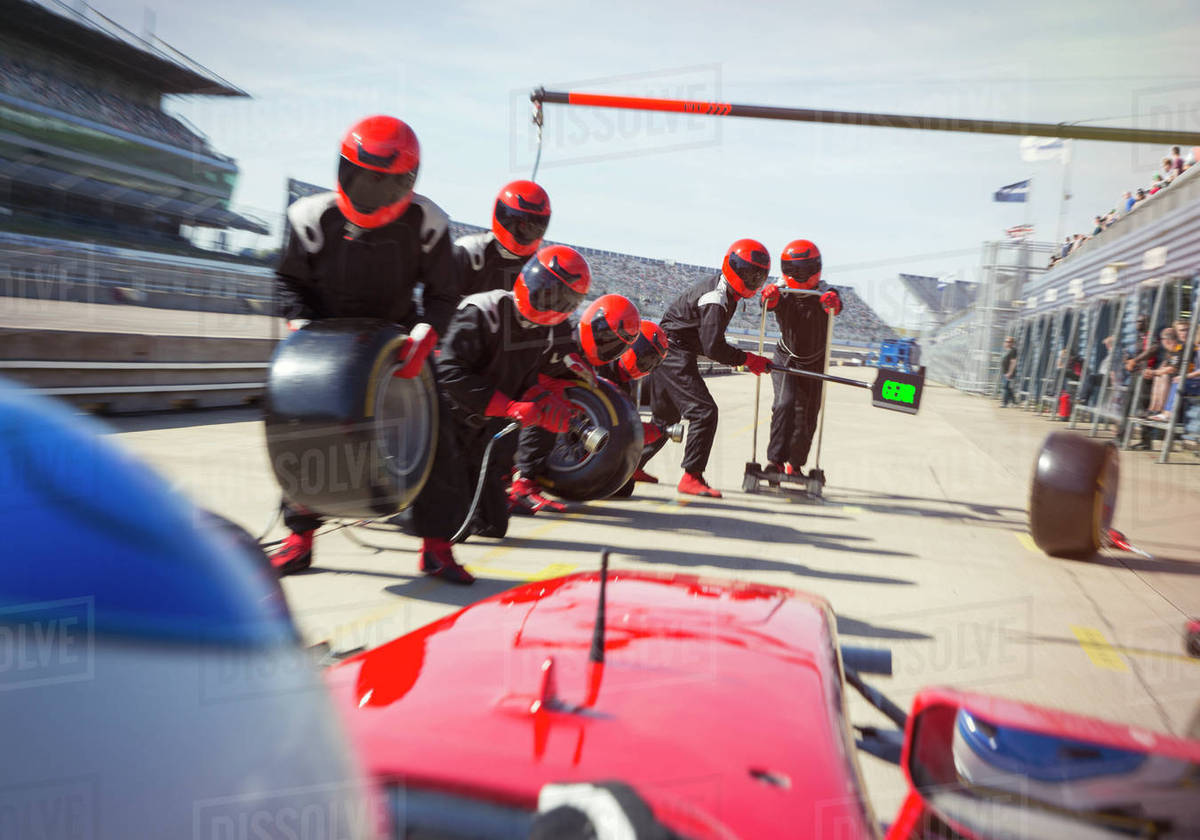 Pit crew with tires ready for nearing formula one race car in pit lane ...