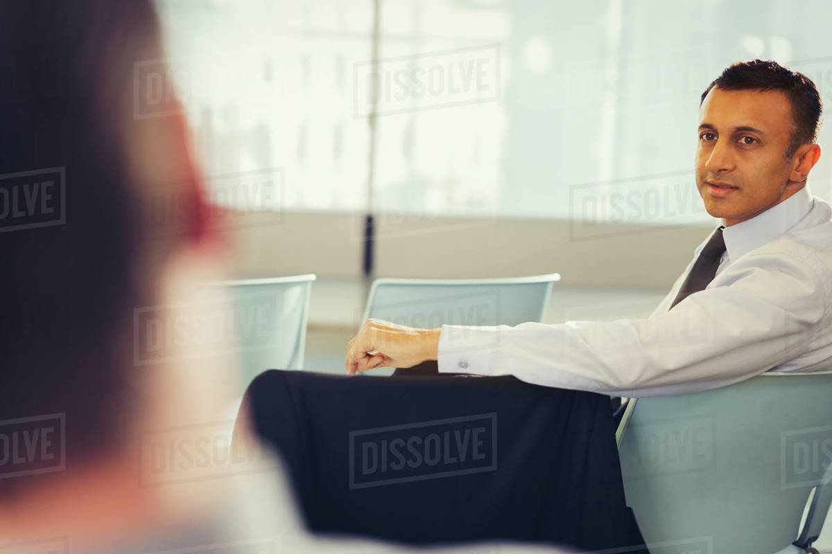 Businessman turning, looking back and listening in conference audience ...