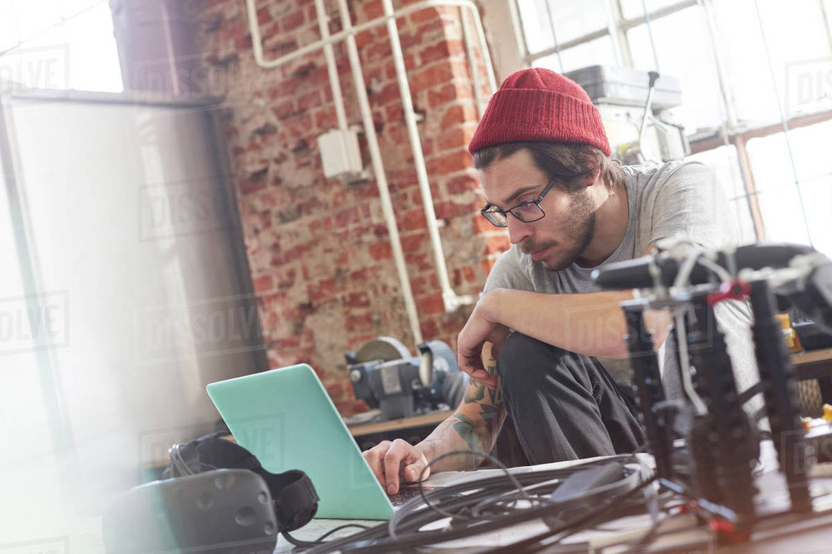 Male computer programmer working at laptop in workshop - Royalty-free ...