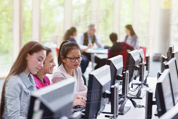 Girl students studying at computer in library - Stock Photo - Dissolve
