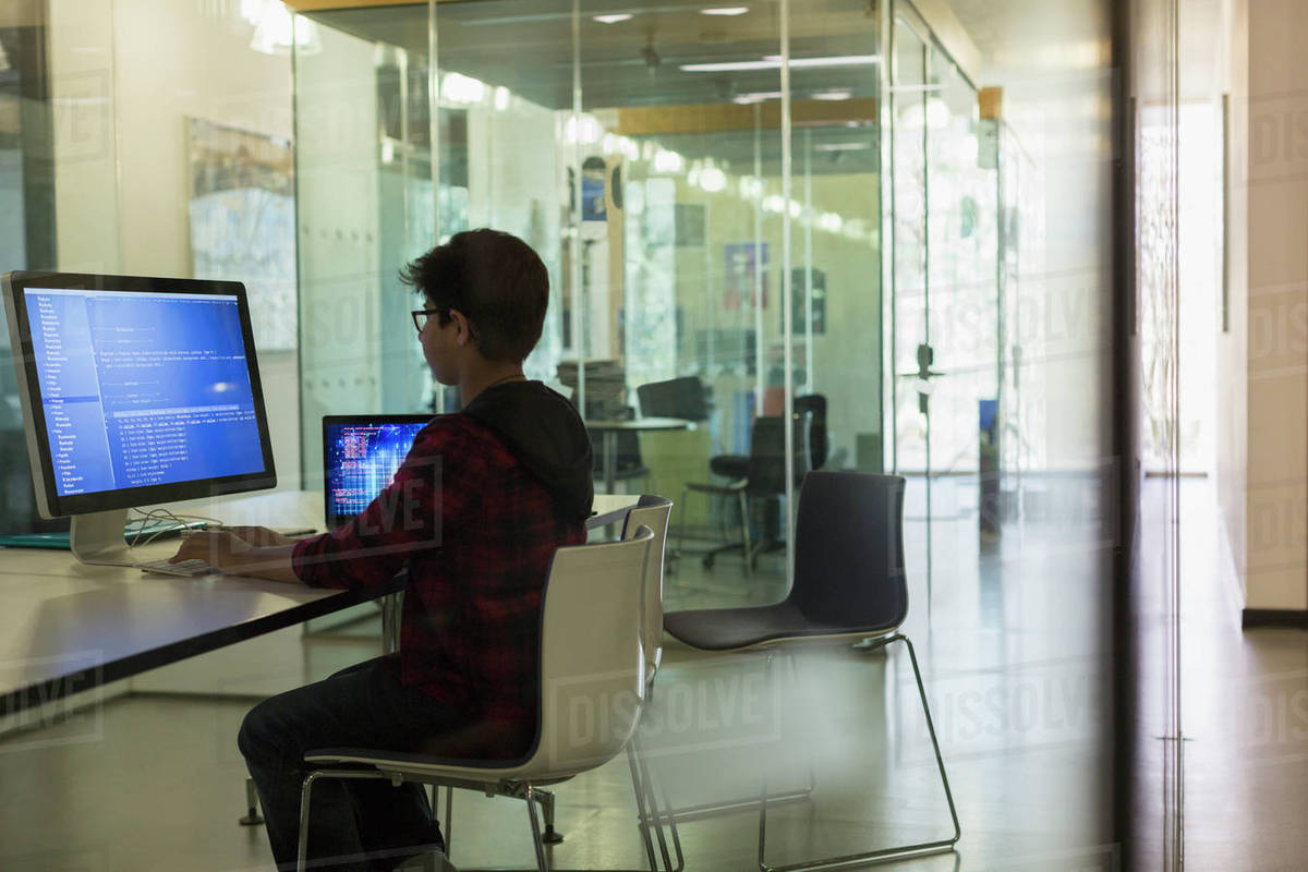 Focused boy student programming at computer in dark classroom - Royalty ...