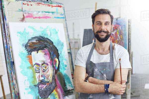 Portrait smiling, confident male artist painting in art studio ...