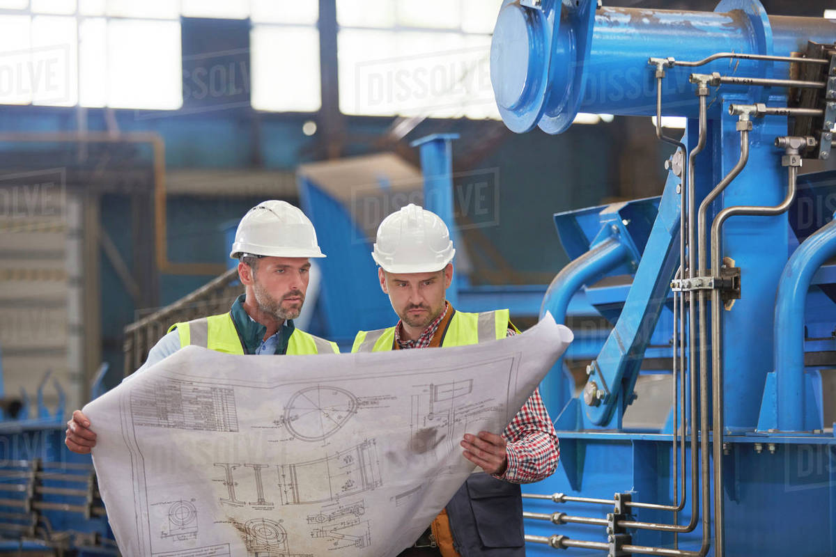 Engineers reviewing blueprints in factory - Royalty-free Stock Photo ...