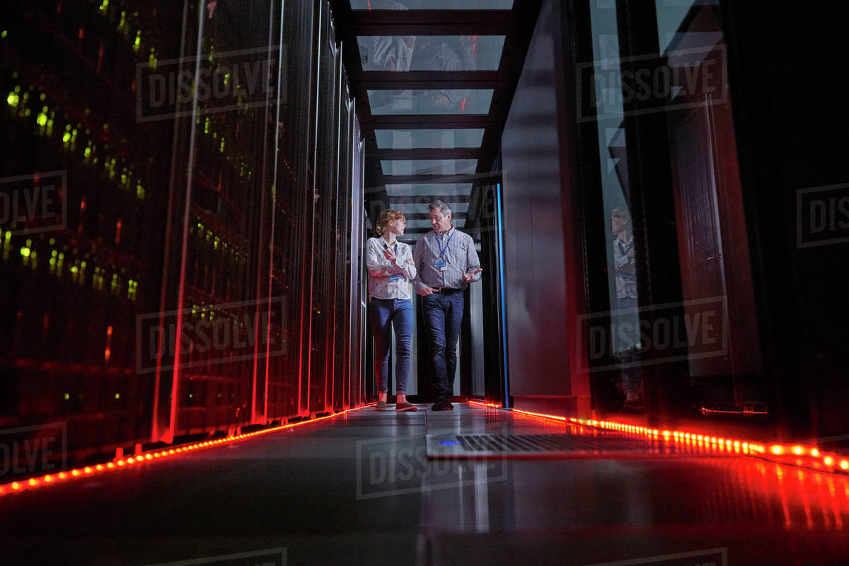 IT technicians talking and walking in dark server room - Royalty-free ...