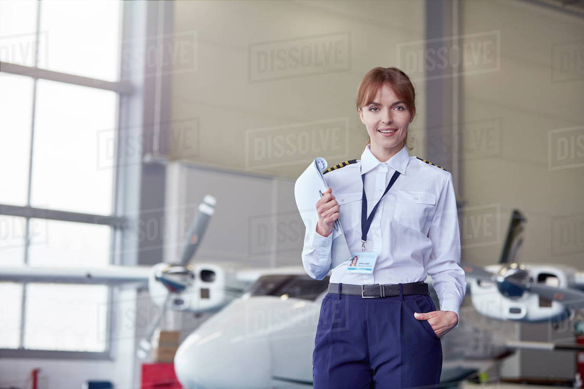 Portrait confident pilot with paperwork in airplane hangar - Stock ...