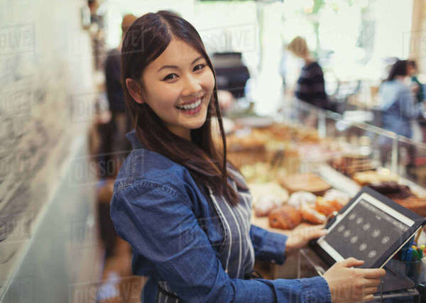 Portrait smiling, confident female cashier at cash register in cafe ...