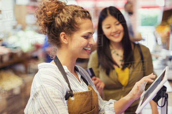 Female cashier helping customer at touch screen cash register in ...