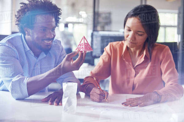 Design professionals examining triangle prototype and sketching in ...
