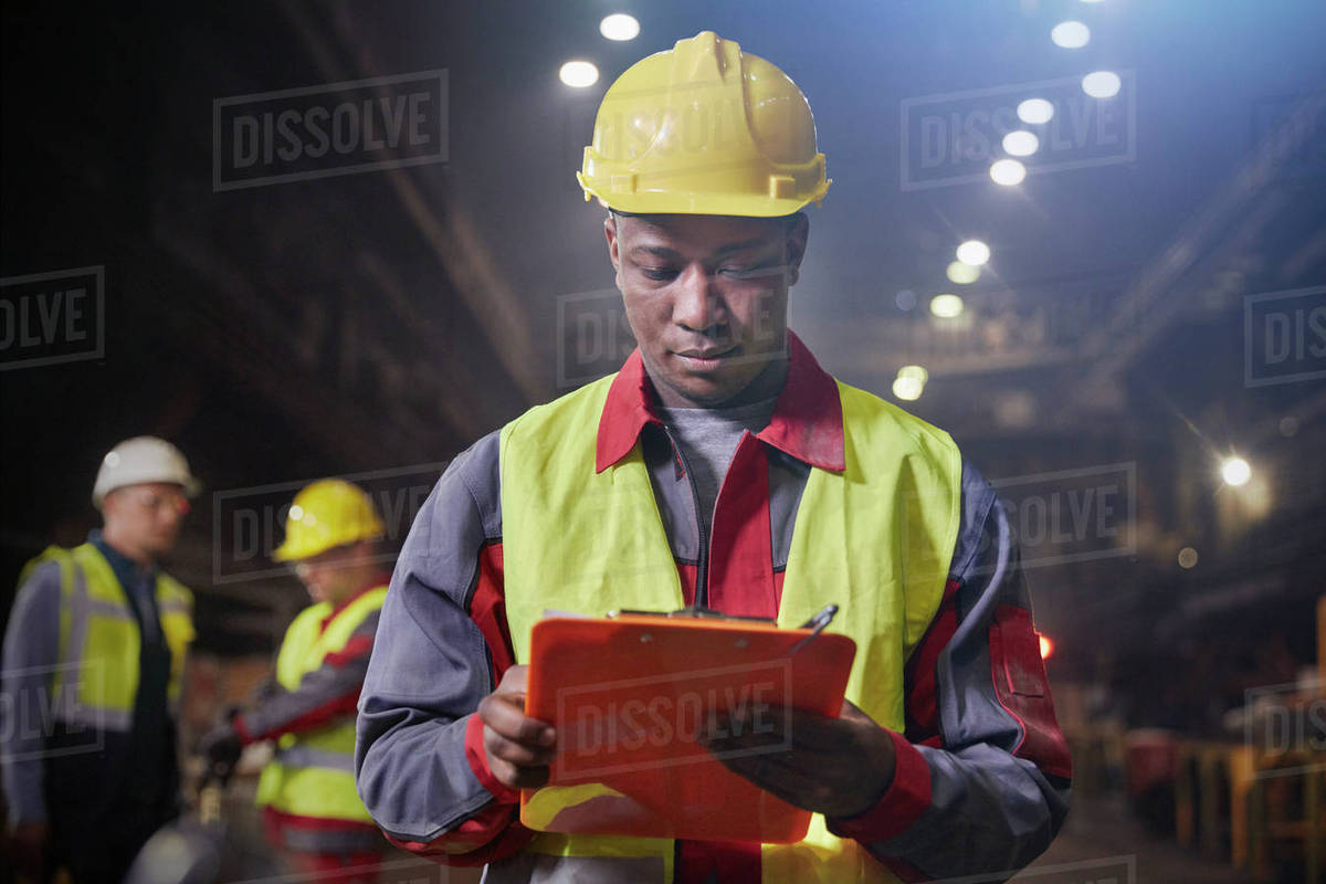 Steelworker with clipboard working in steel mill - Stock Photo - Dissolve