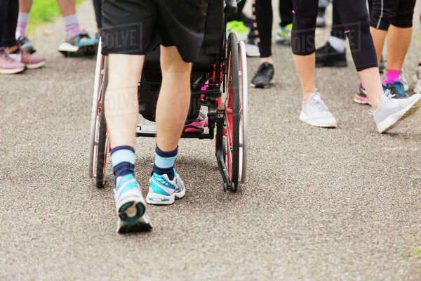 Man pushing wheelchair on crowded path - Royalty-free Stock Photo ...