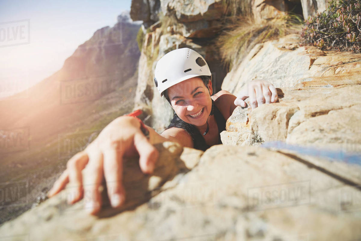 Portrait smiling, confident rock climber reaching for rock - Royalty ...