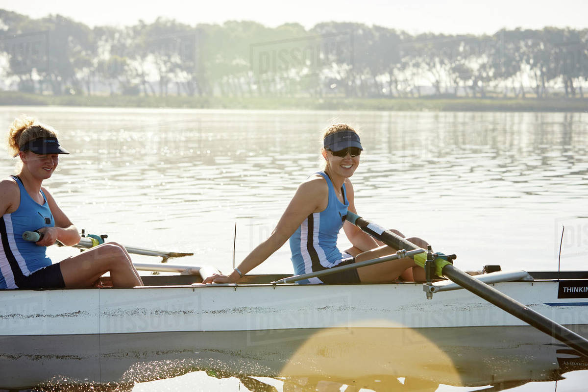 Portrait smiling female rower in scull on sunny lake - Stock Photo ...