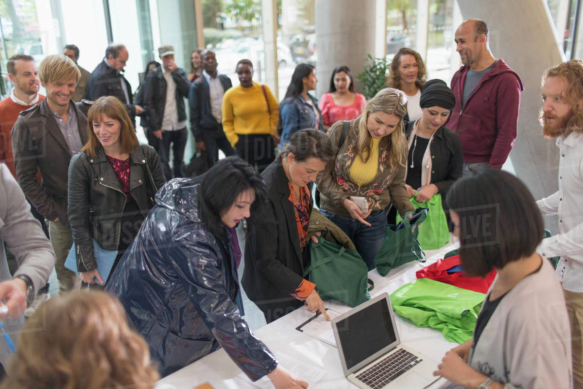 Business people arriving, checking in at conference registration table ...
