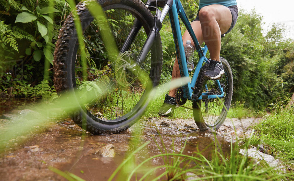 Woman mountain biking on muddy trail - Stock Photo - Dissolve