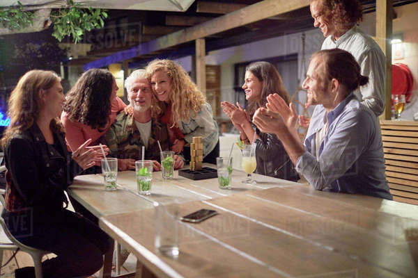 Happy friends clapping, celebrating on patio at night - Royalty-free ...