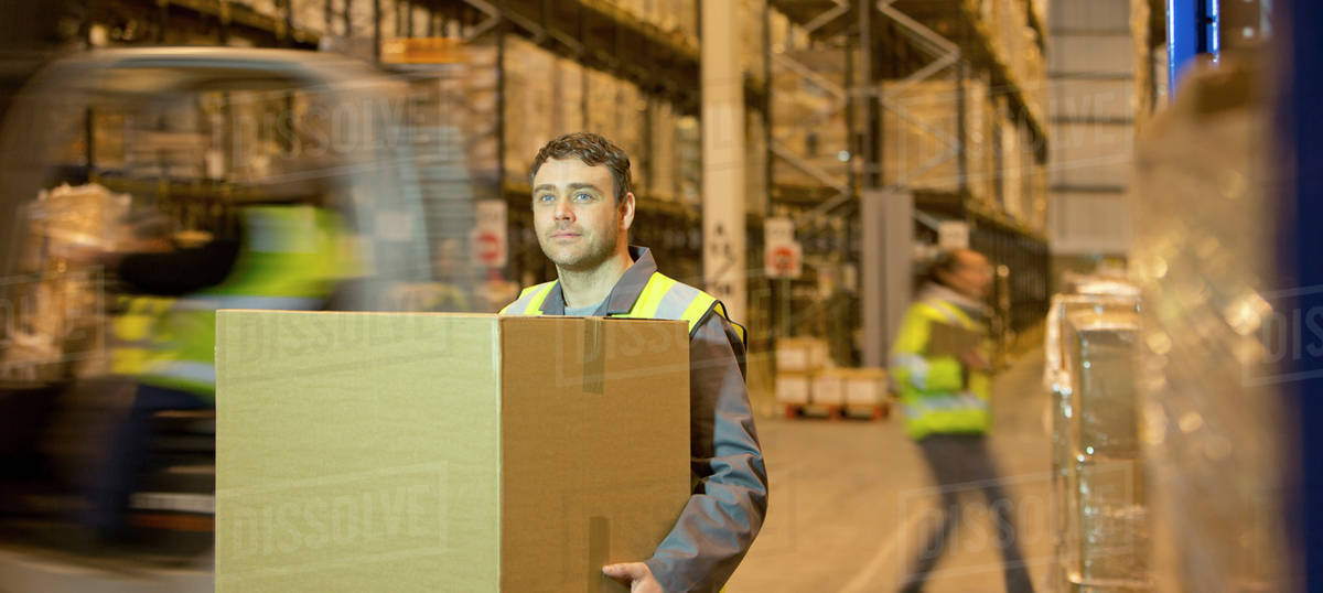 Worker carrying box in warehouse - Royalty-free Stock Photo | Dissolve