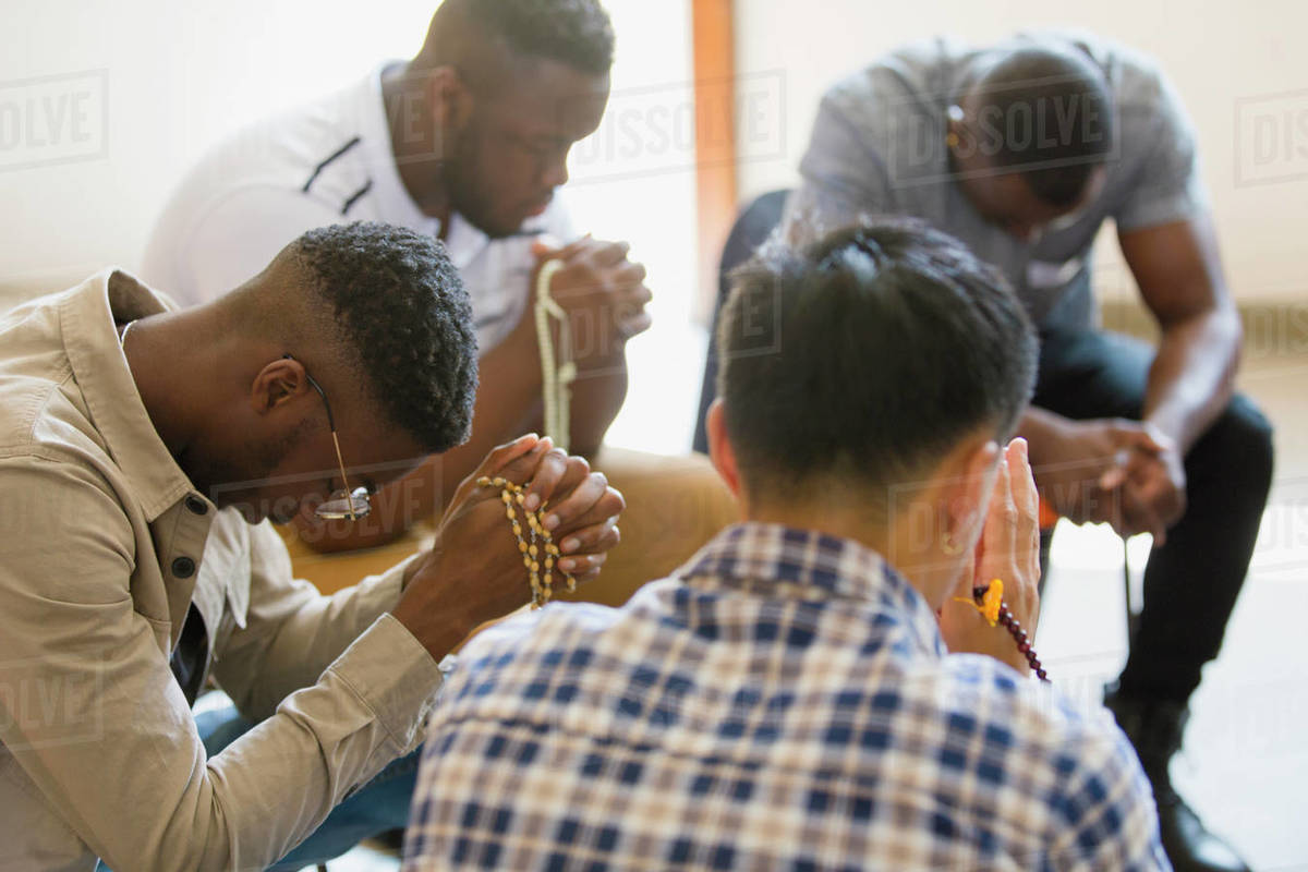 Men praying with rosaries in prayer group - Stock Photo - Dissolve