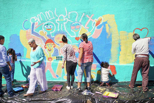 Community volunteers painting vibrant mural on sunny wall - Royalty ...