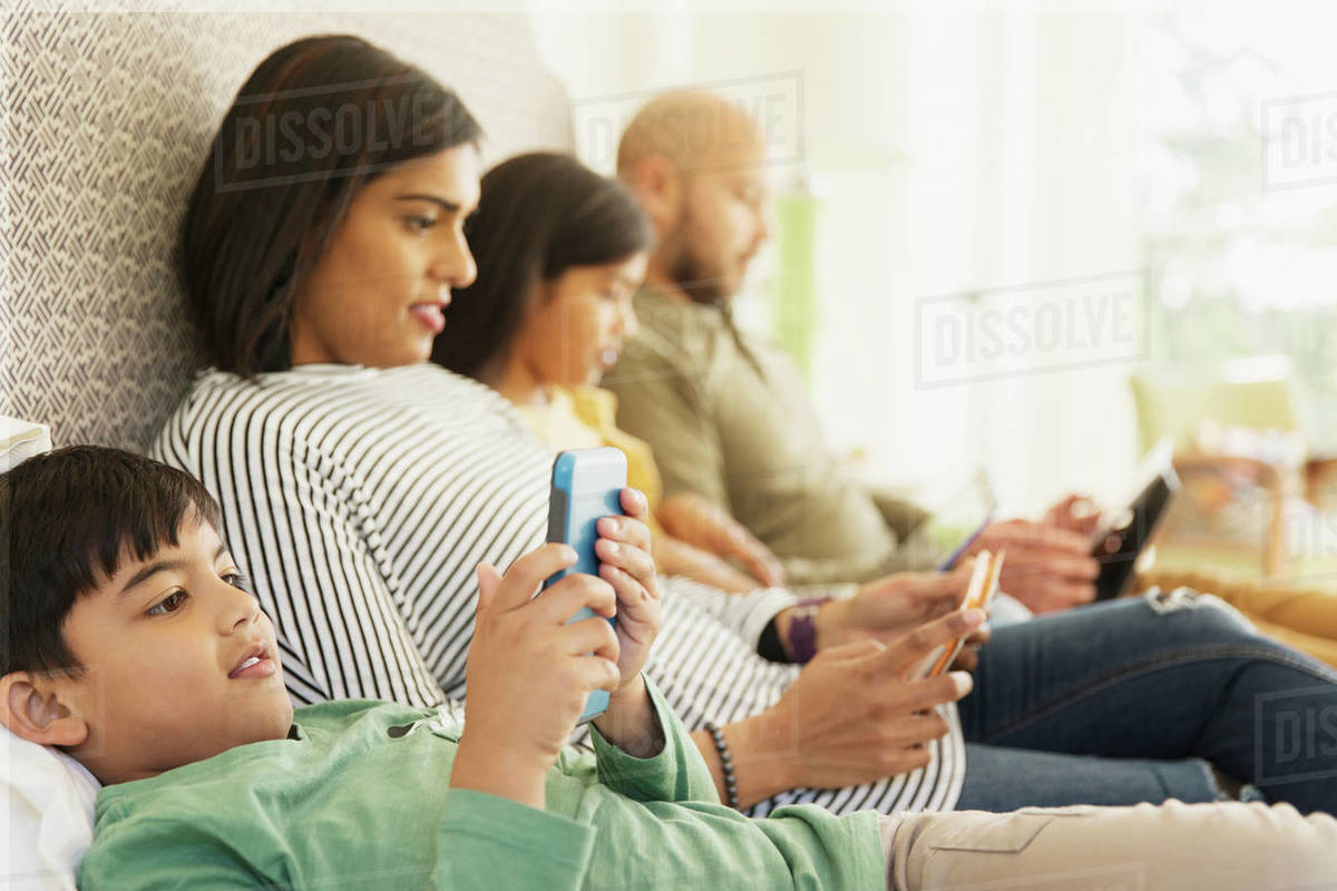 Family using technology on bed - Royalty-free Stock Photo | Dissolve