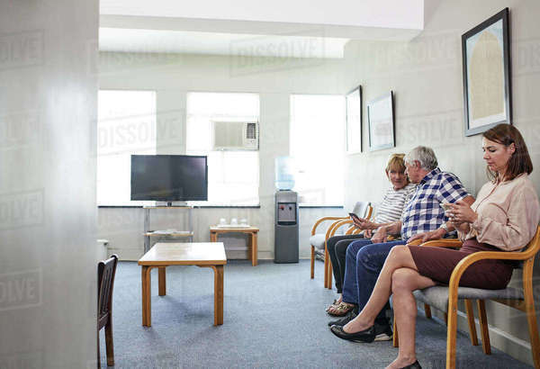 Patients waiting, using smart phones in clinic waiting room - Royalty ...