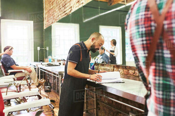 Male barber looking at schedule in barbershop - Royalty-free Stock ...