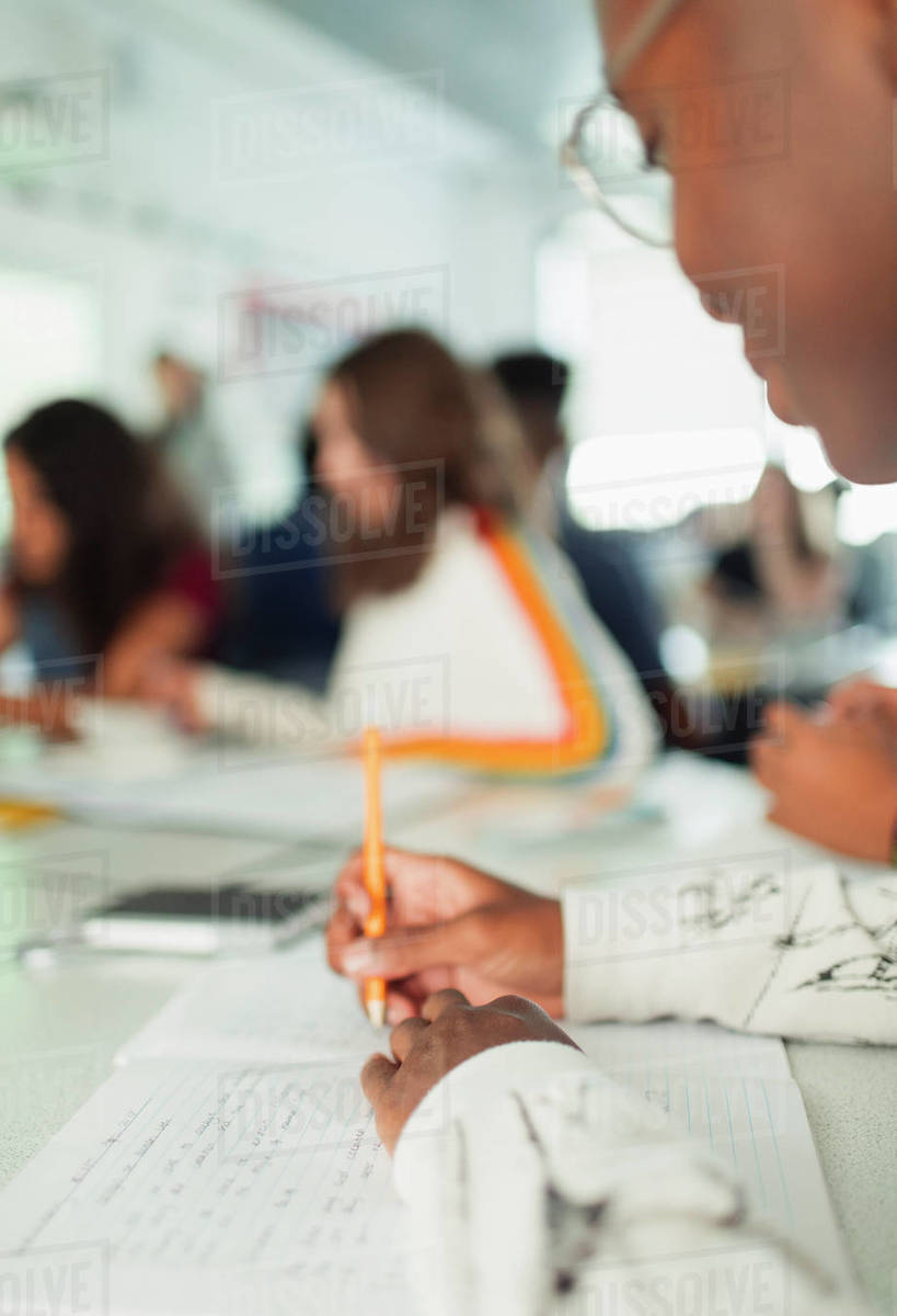 High school boy student taking notes, writing in notebook in classroom ...