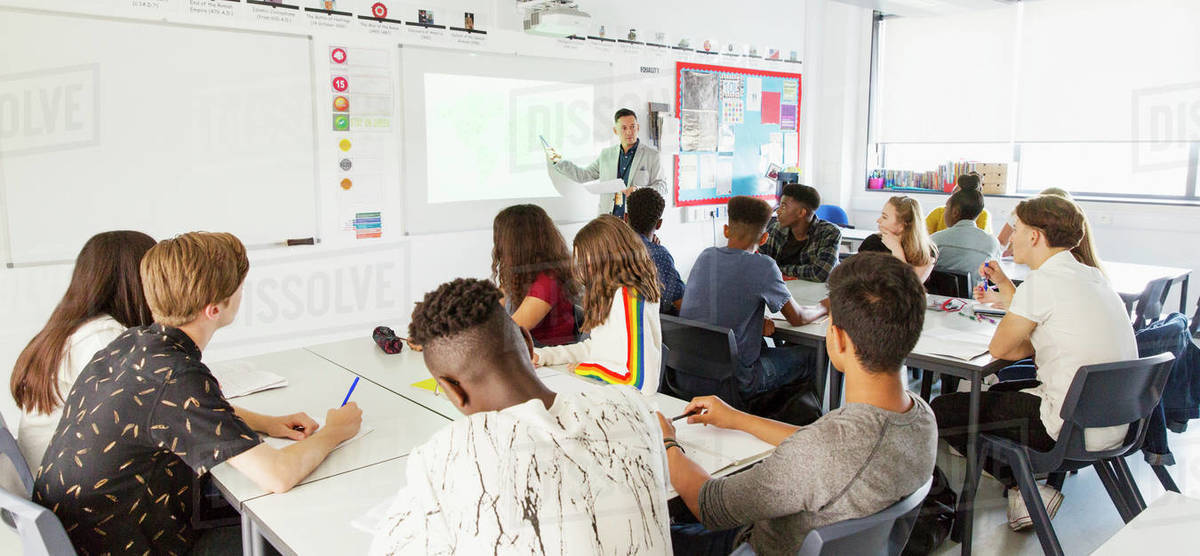 High school students watching teacher at projection screen during ...