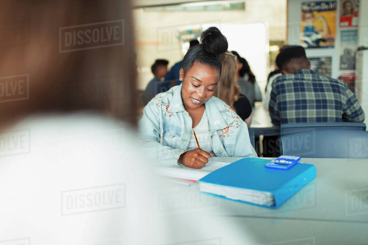 High school girl student doing homework at table in classroom - Royalty ...