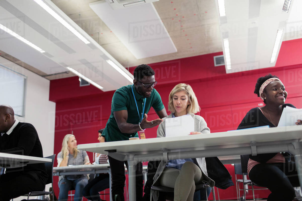 Community college instructor helping student with paperwork in ...