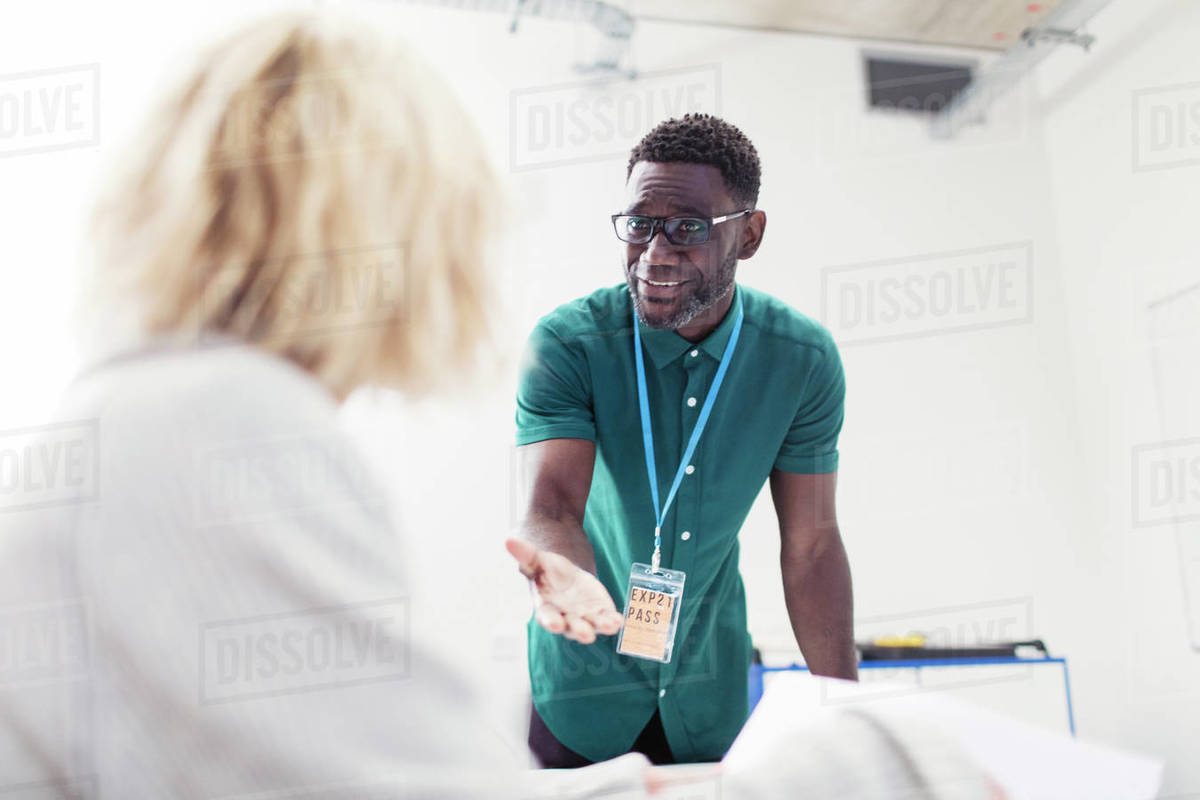 Male community college instructor talking with student in classroom ...