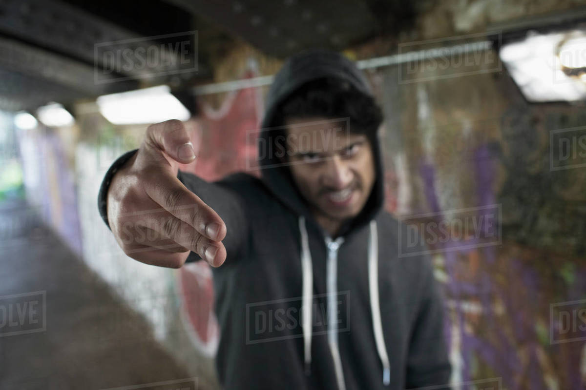 Portrait menacing young man gesturing finger gun in urban tunnel ...