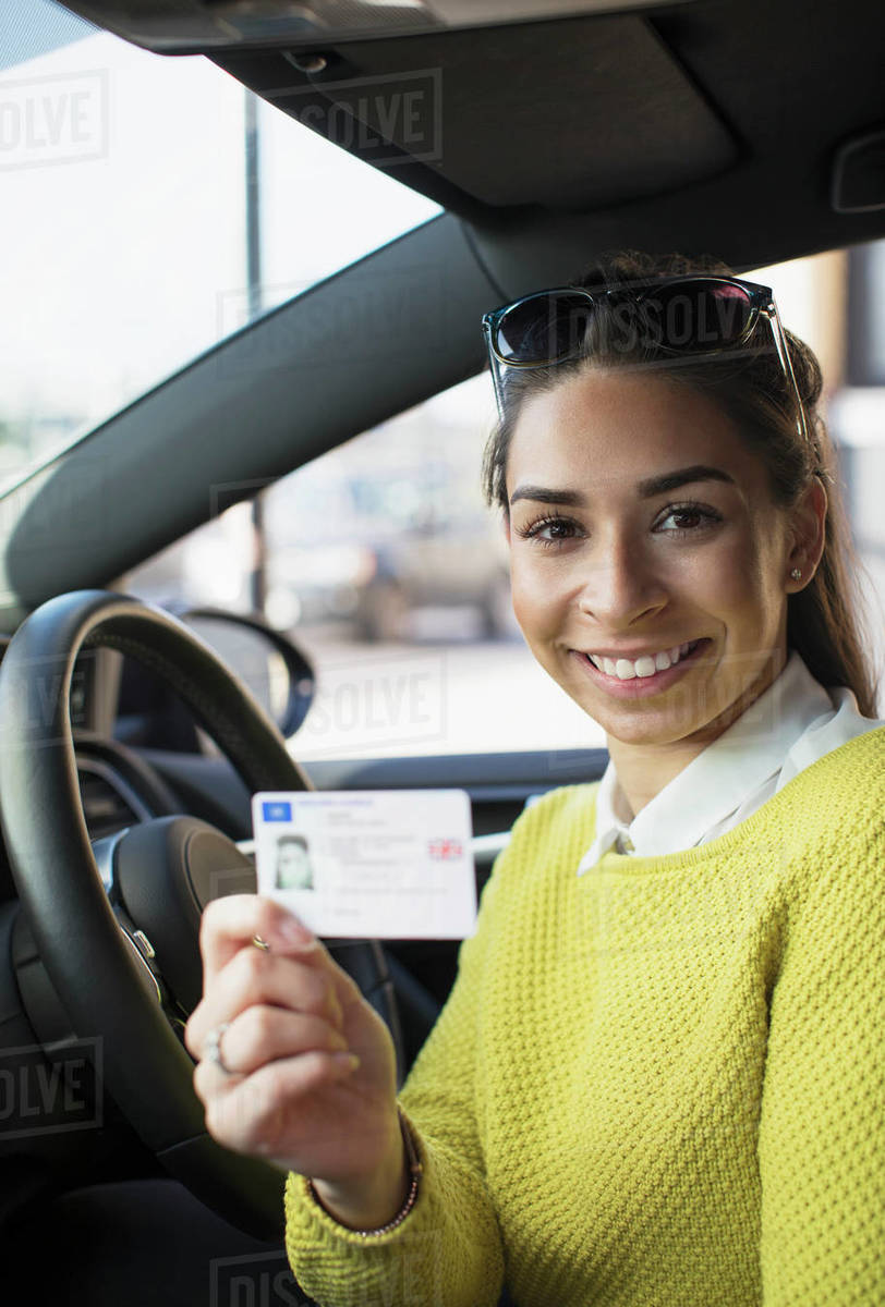 Portrait happy young woman holding new drivers license in car - Royalty ...