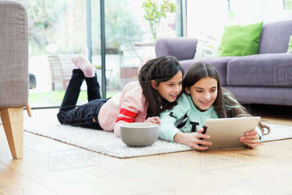Girls watching movie with digital tablet on living room floor - Stock ...