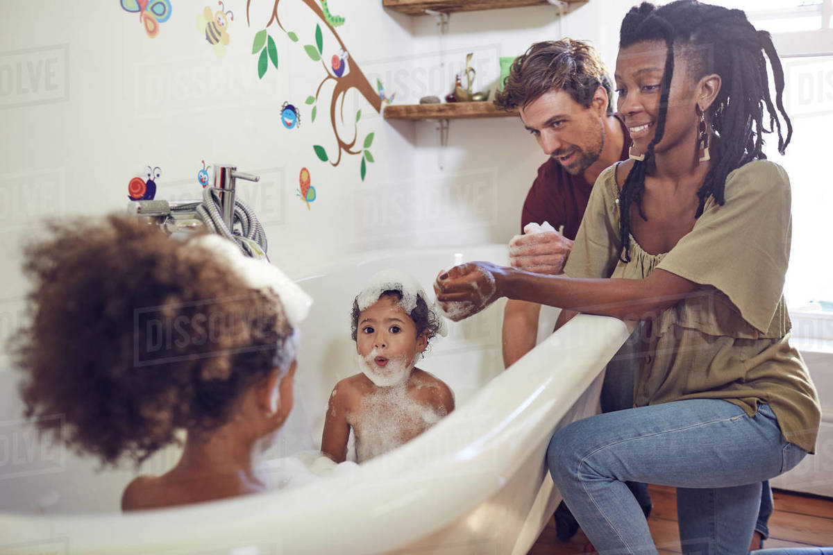 Parents giving toddler daughters bubble bath - Stock Photo - Dissolve