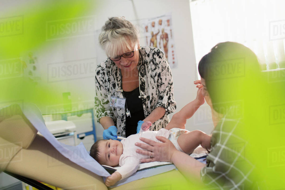 Female pediatrician examining baby girl on examination room table ...