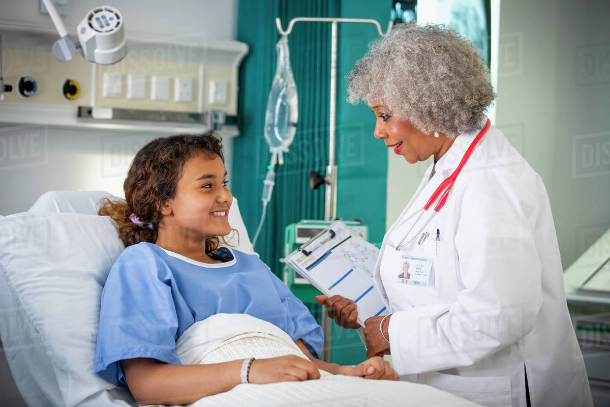 Female doctor talking with girl patient in hospital room - Royalty-free ...