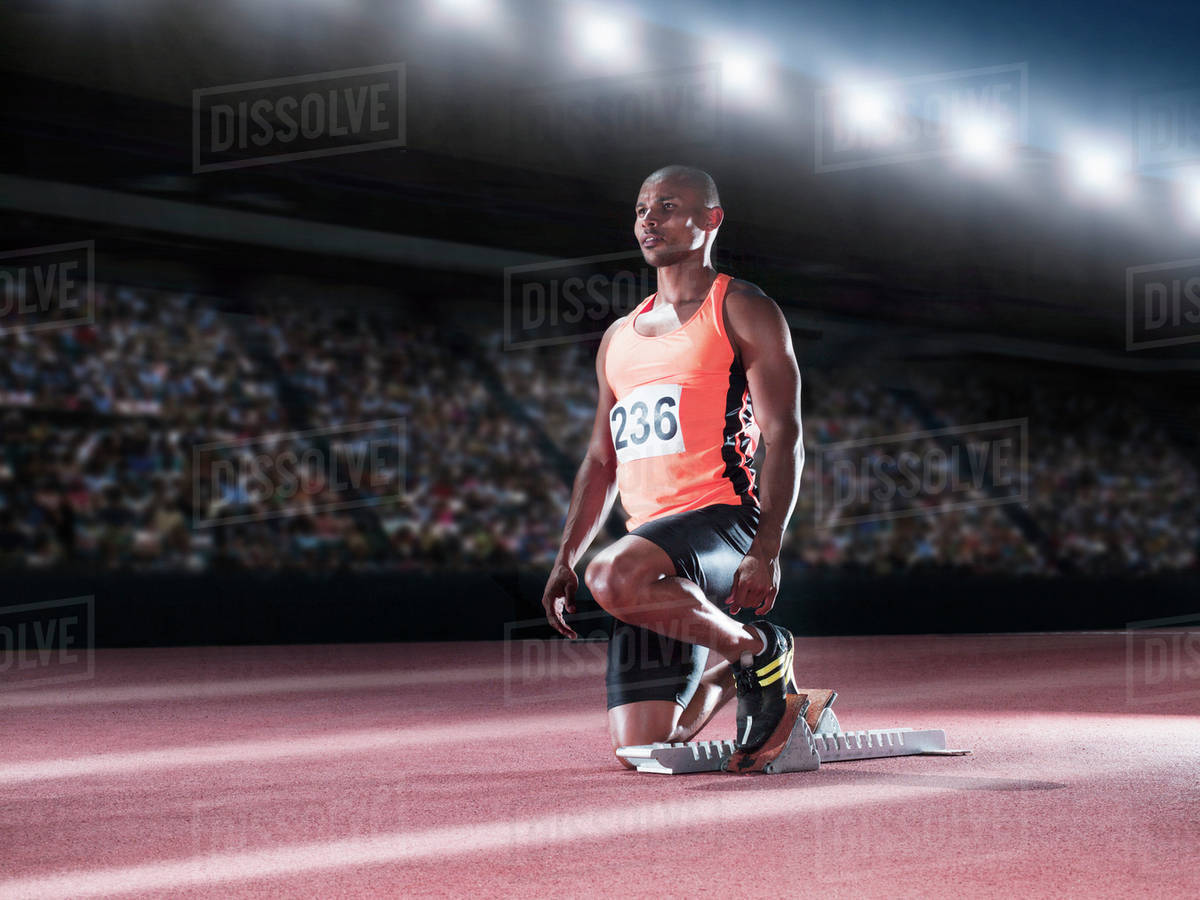 Runner with feet in starting block on track - Stock Photo - Dissolve