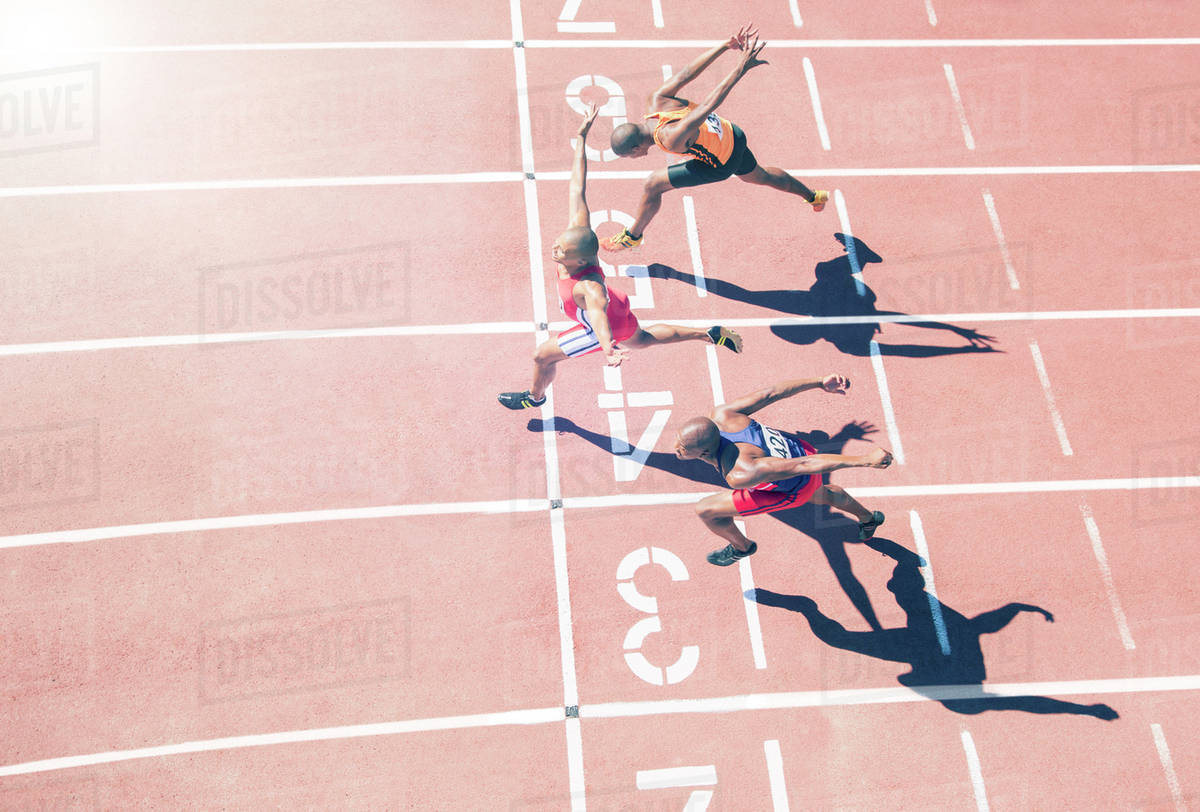 Runners crossing finish line on track - Stock Photo - Dissolve