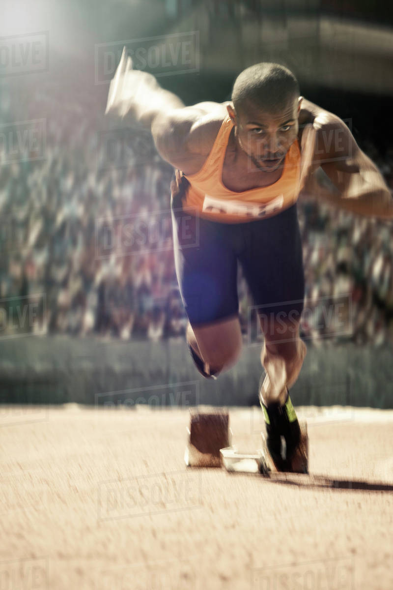 Runner taking off from starting block on track - Stock Photo - Dissolve