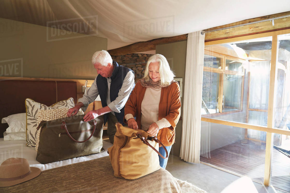 Senior couple unpacking bags in hotel room - Royalty-free Stock Photo ...