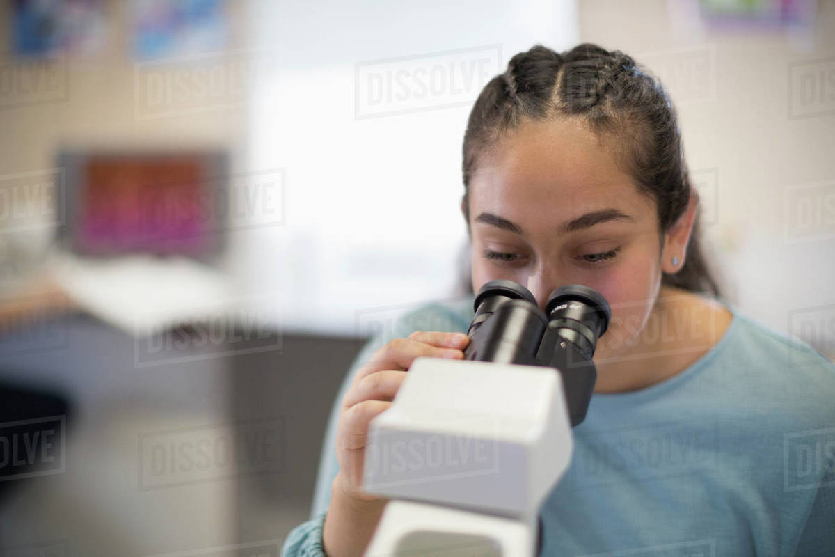 Girl student using microscope in classroom - Stock Photo - Dissolve