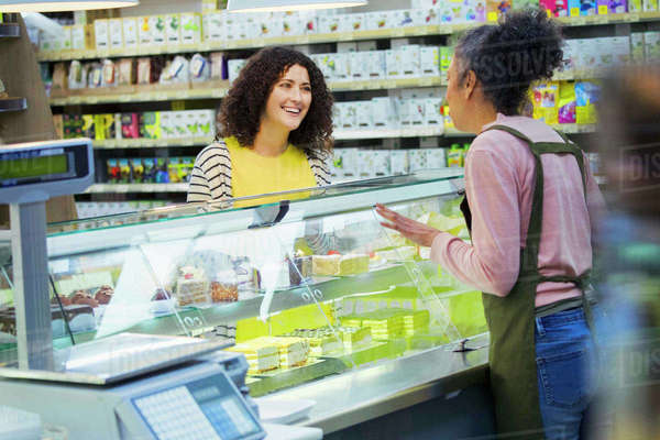 Female worker helping customer at bakery display case in supermarket ...