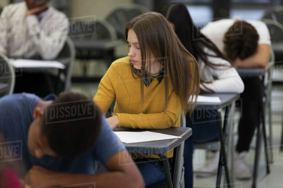 Focused high school girl student taking exam at desk in classroom ...
