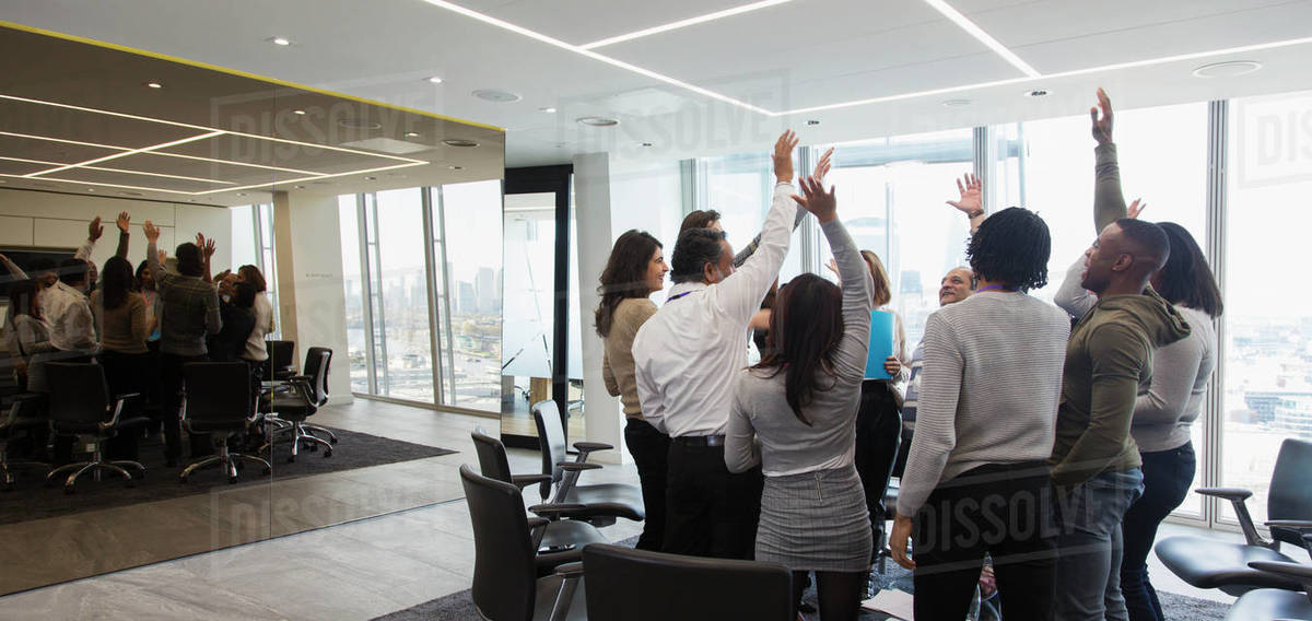 Business people cheering in huddle in office meeting - Royalty-free ...