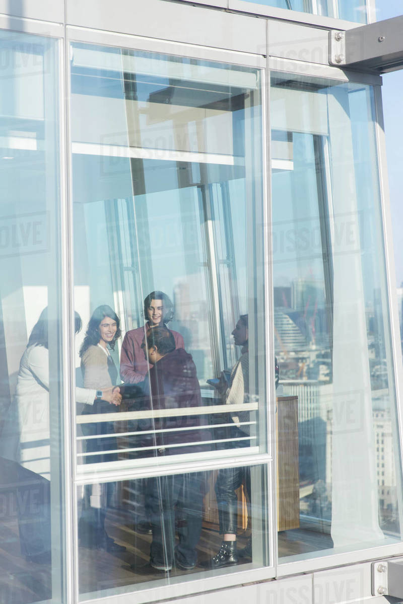 Business people talking at sunny office window - Stock Photo - Dissolve