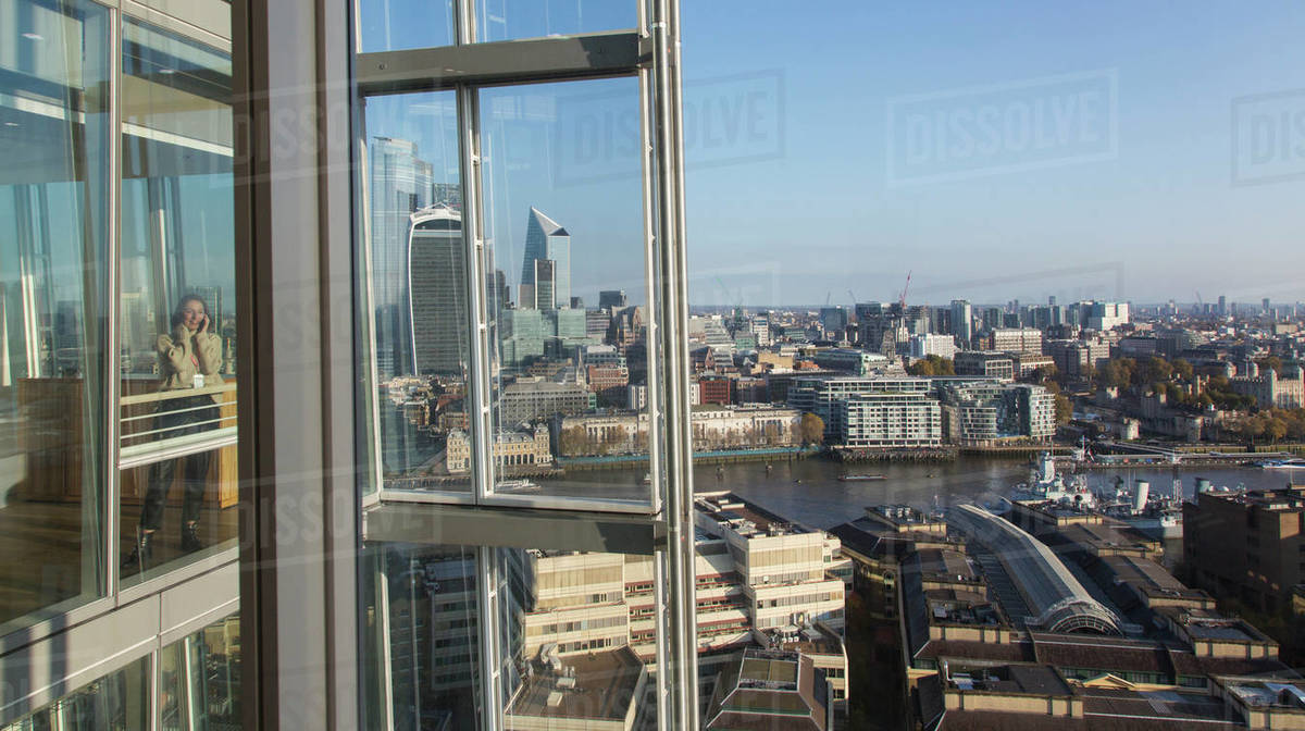 Businesswoman using smart phone at urban highrise office window - Stock ...