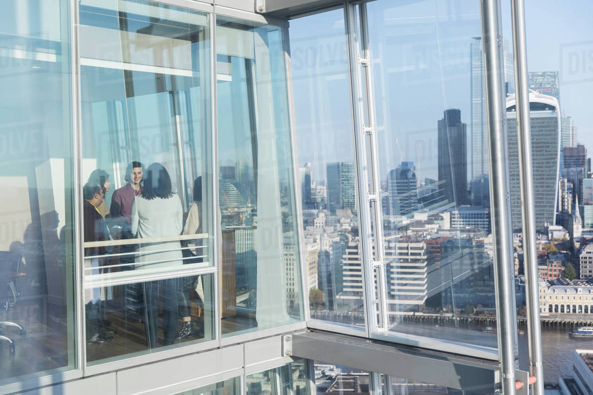 Business people talking at sunny urban highrise office window - Stock ...